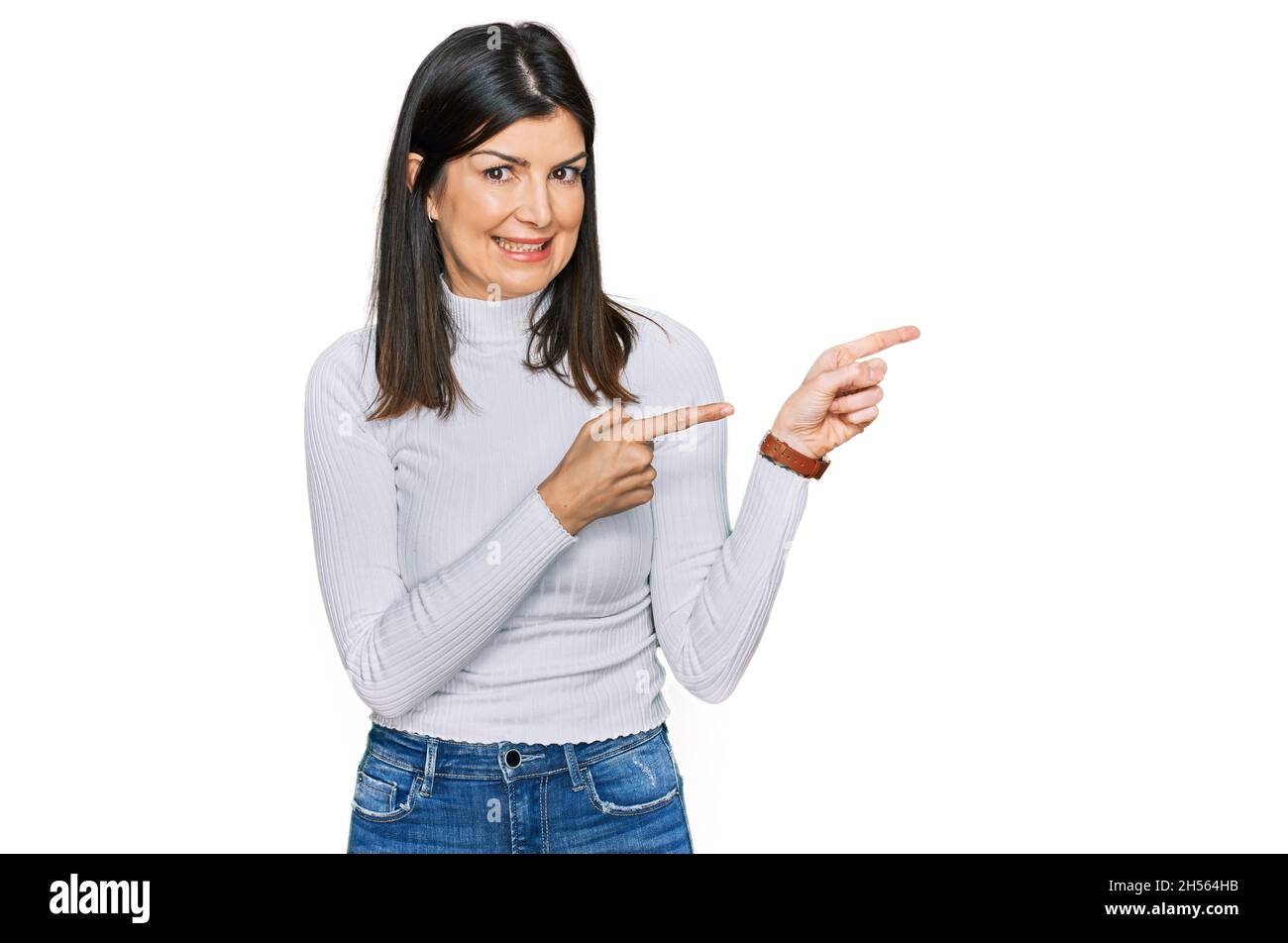 Beautiful brunette woman wearing casual clothes pointing aside worried ...