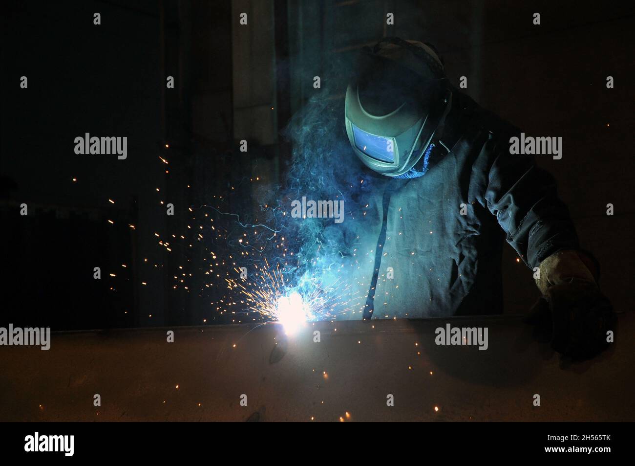 Electric welder at work. A worker welds metal structures at a factory ...
