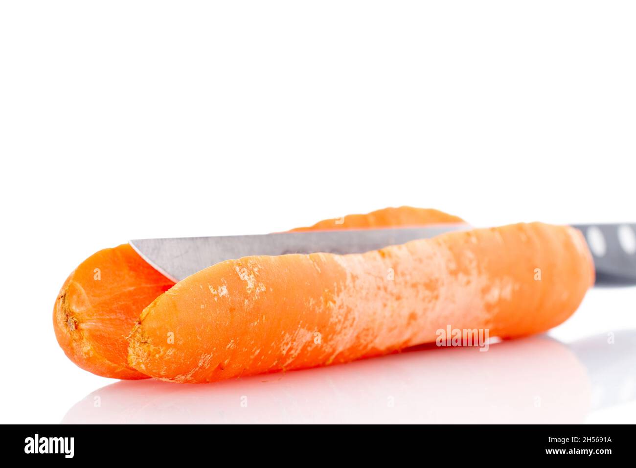 One ripe organic, unpeeled carrot cut in half with a metal knife, close ...