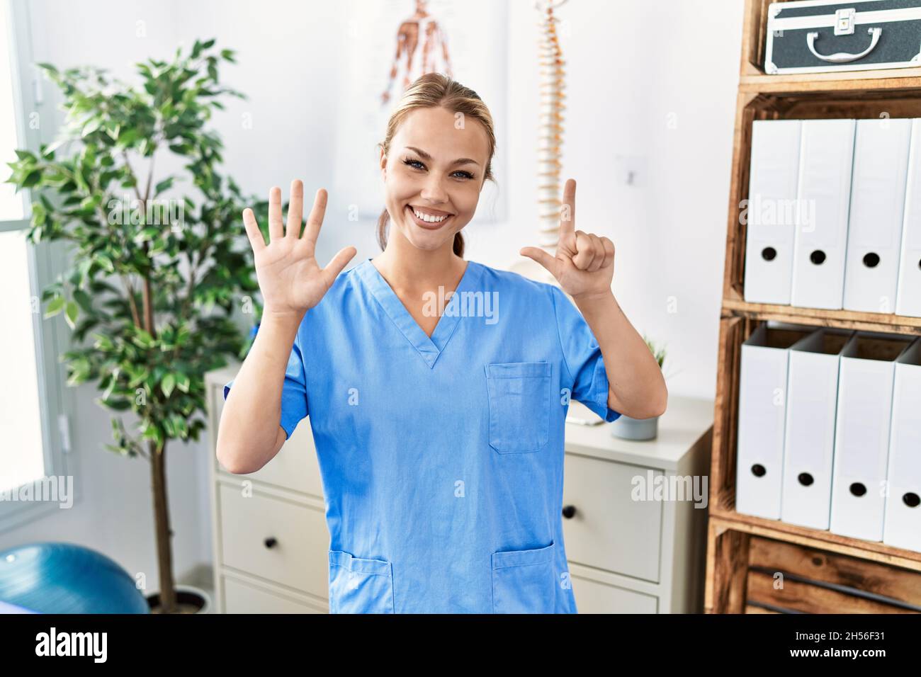 Young caucasian woman working at pain recovery clinic showing and ...