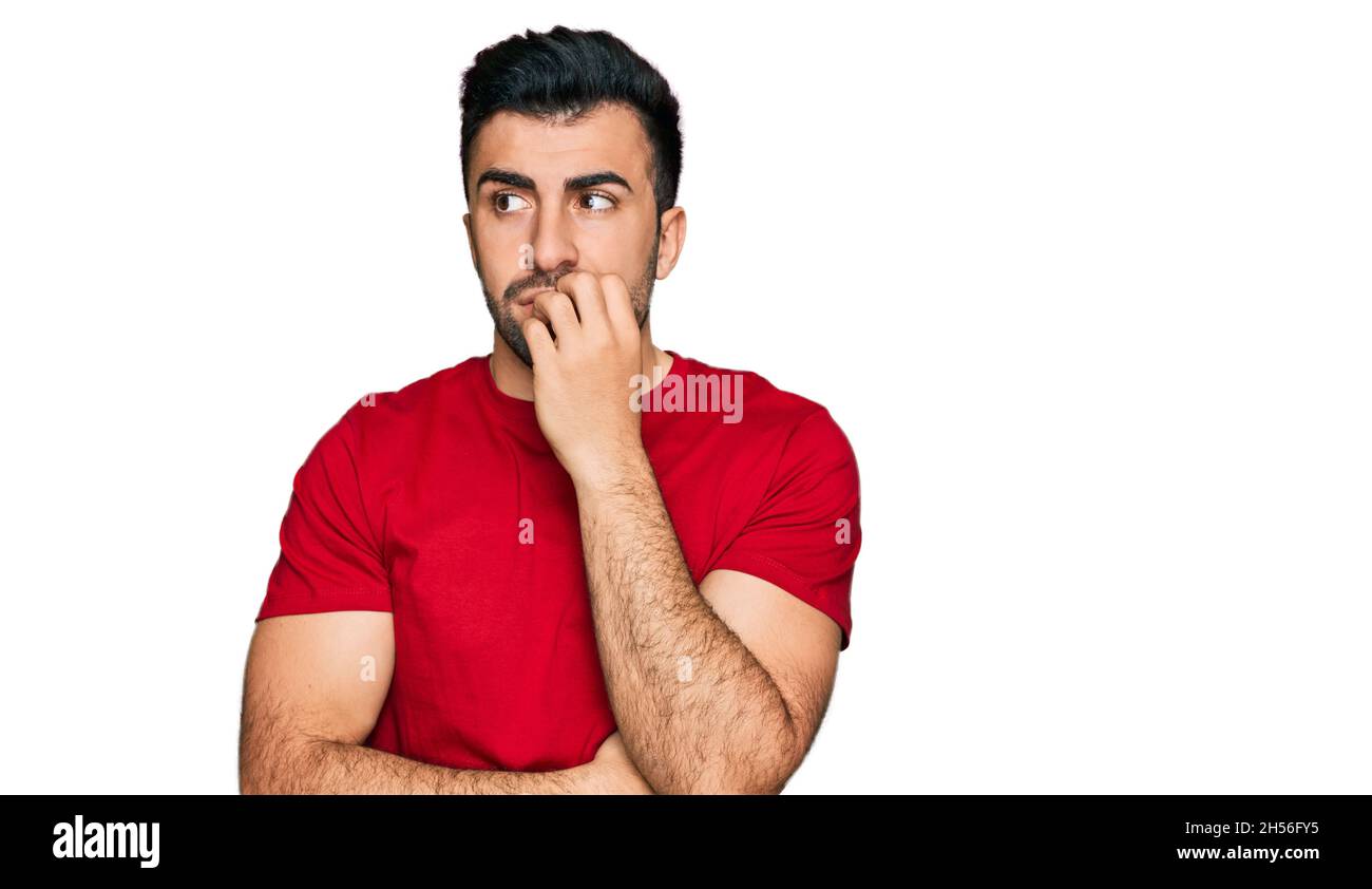 Hispanic man with beard wearing casual red t shirt looking stressed and ...
