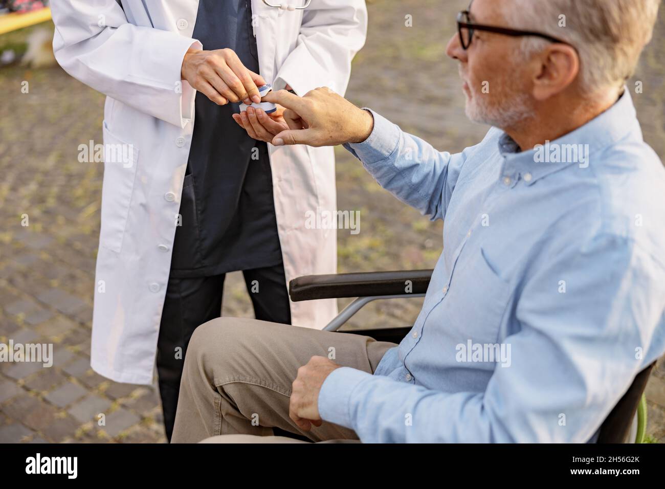 Doctor examining handicapped male patient in wheelchair with fingertip ...