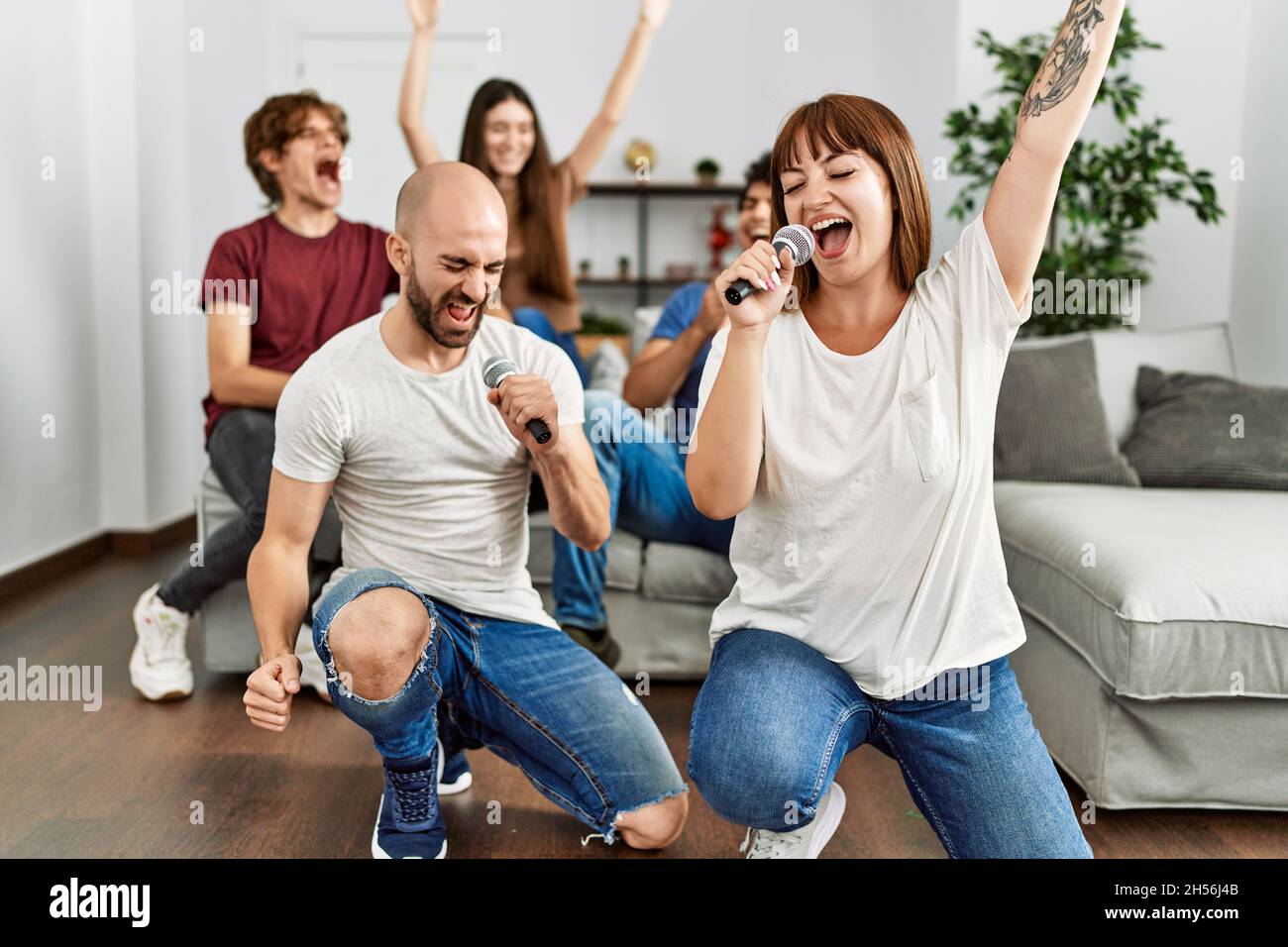 Group of young friends having party singing song using microphone at ...