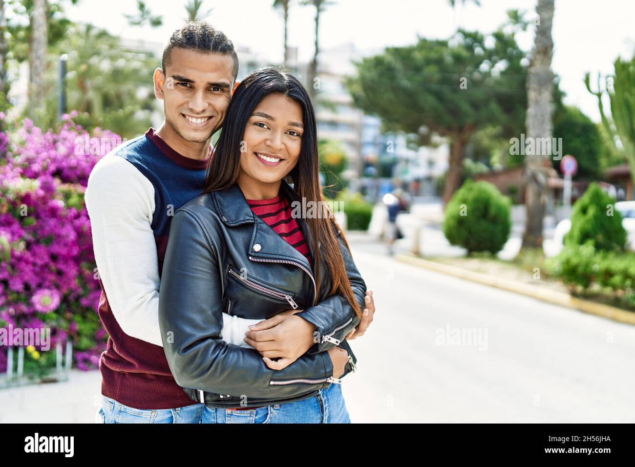 Young latin couple smiling happy and hugging walking at the street of ...