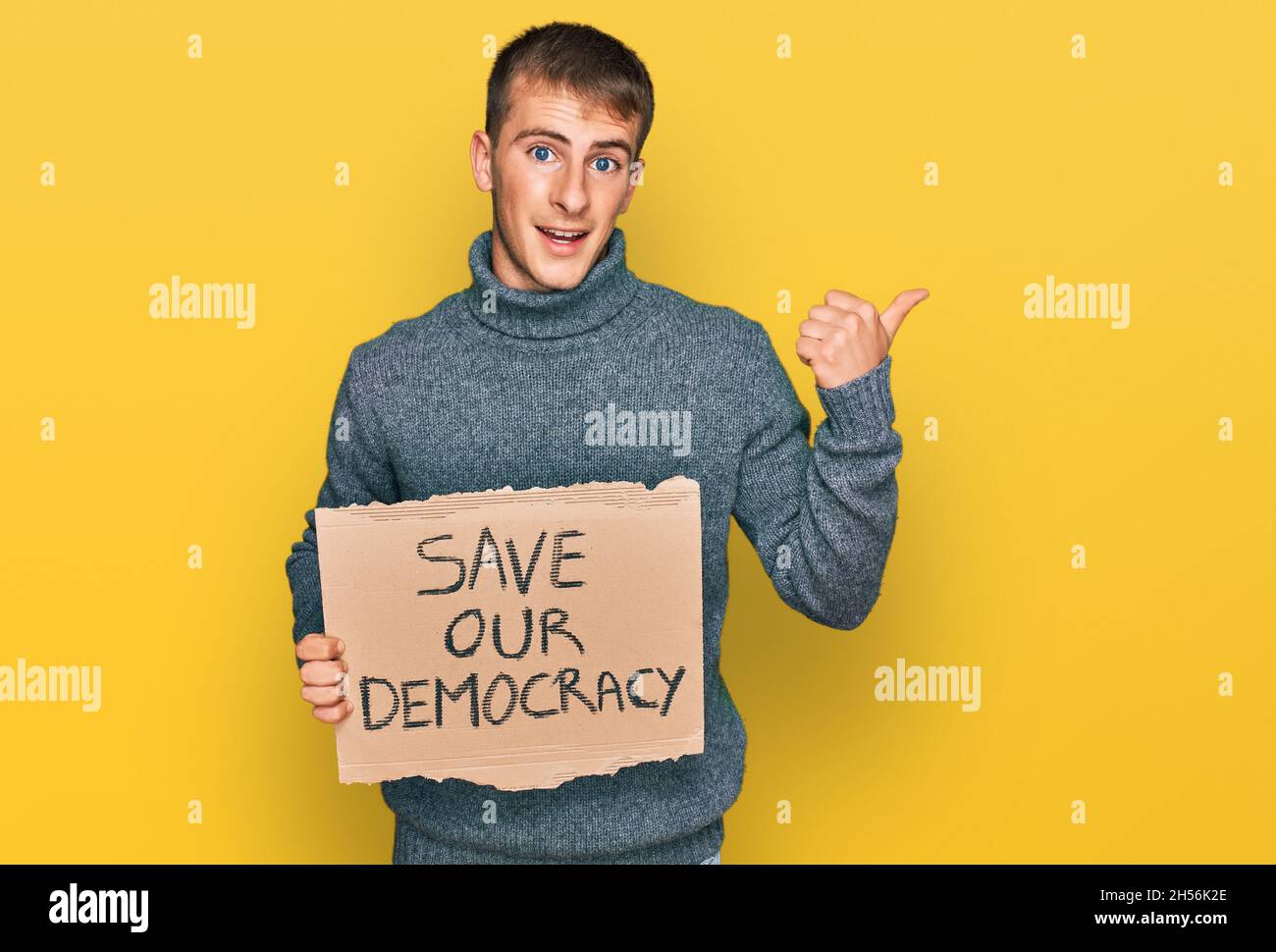 Young blond man holding save our democracy protest banner pointing ...