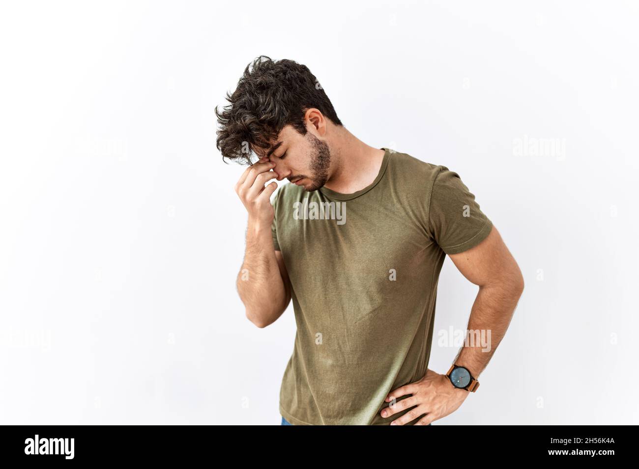 Hispanic man standing over isolated white background tired rubbing nose ...