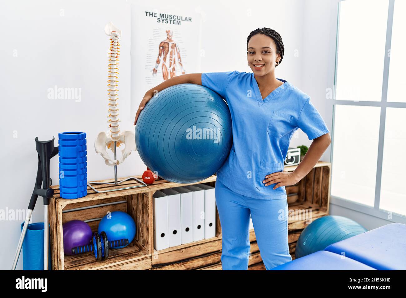Young african american woman wearing physio therapist uniform holding ...