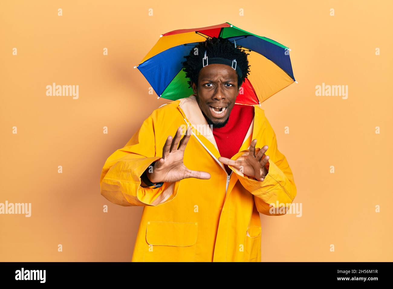 Young african american man wearing yellow raincoat afraid and terrified ...