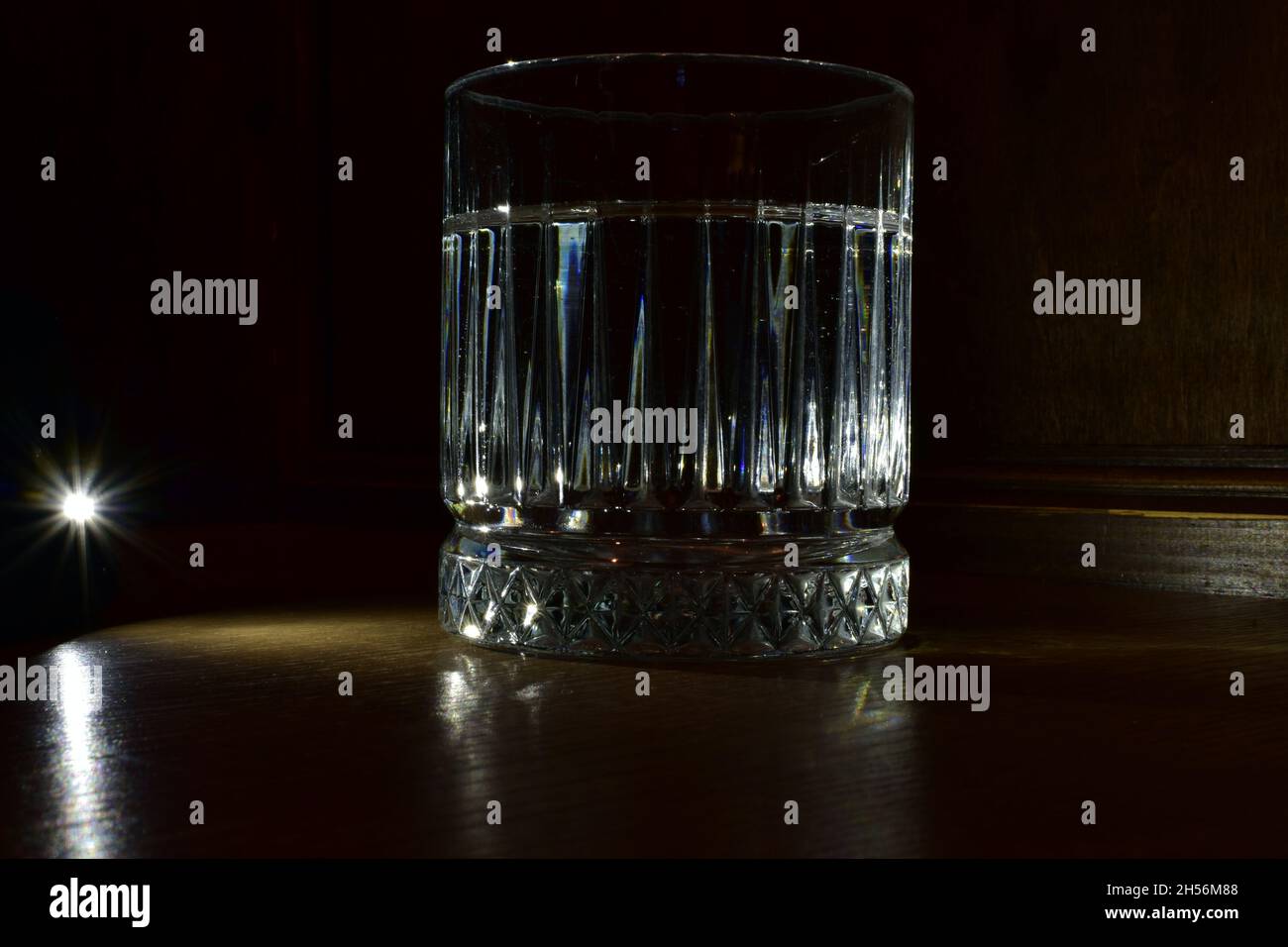 Sharp edges of a glass close up on table in dark lighting Stock Photo ...