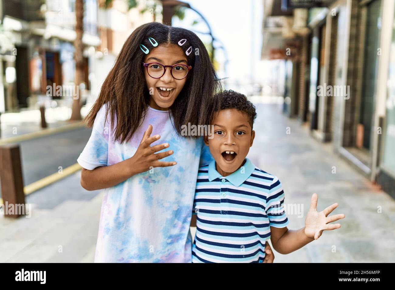 African american family of bother and sister standing at the street celebrating victory with ...