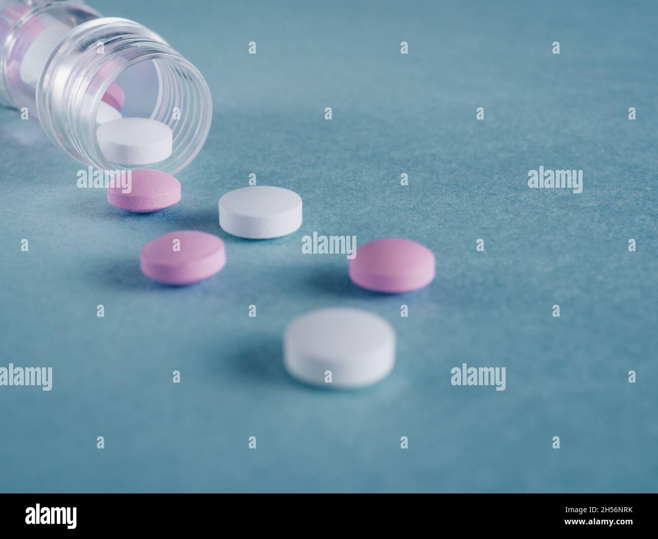 Group of pink and white round medicine pills and bottle on a blue ...