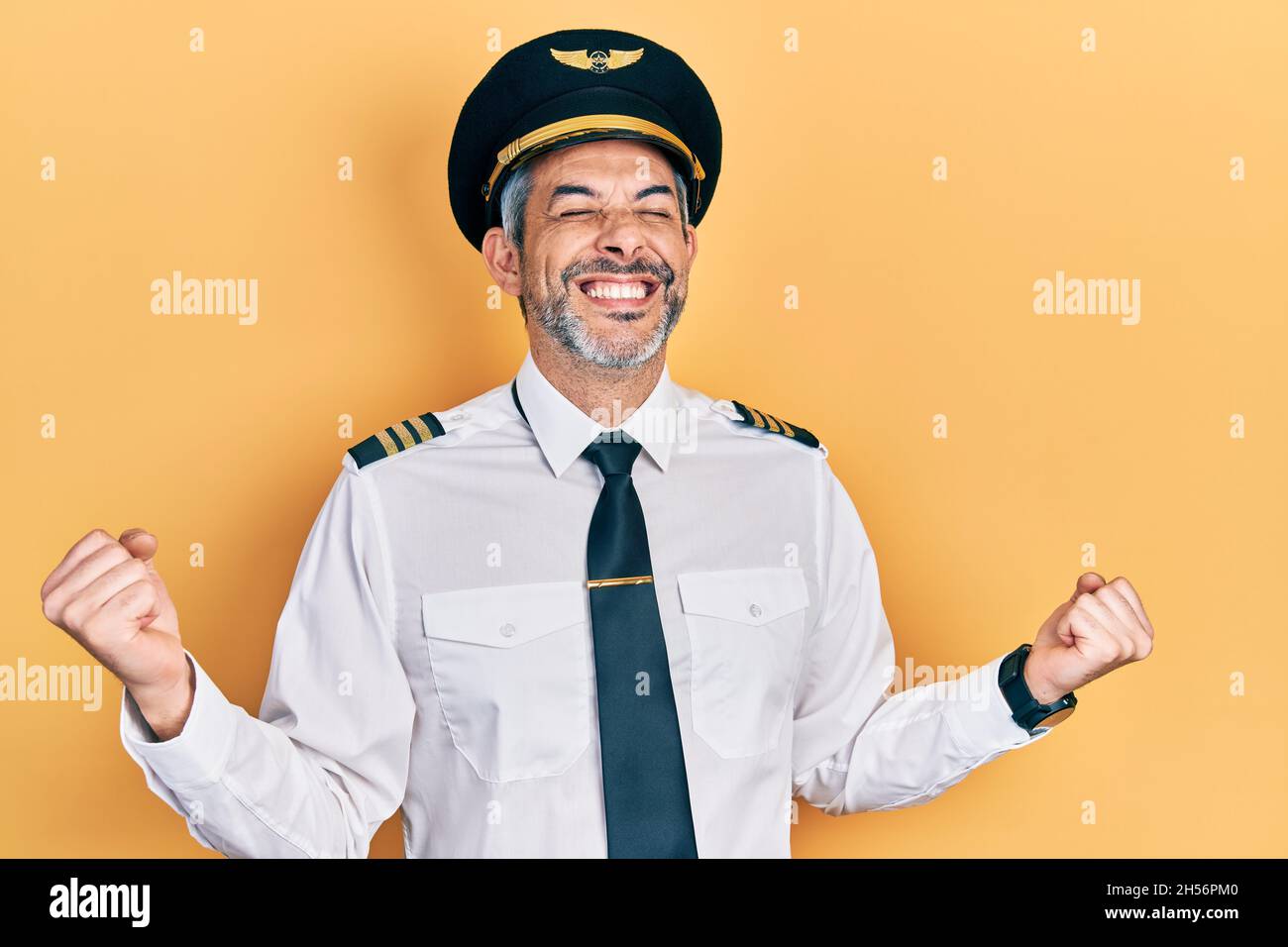 Handsome middle age man with grey hair wearing airplane pilot uniform ...
