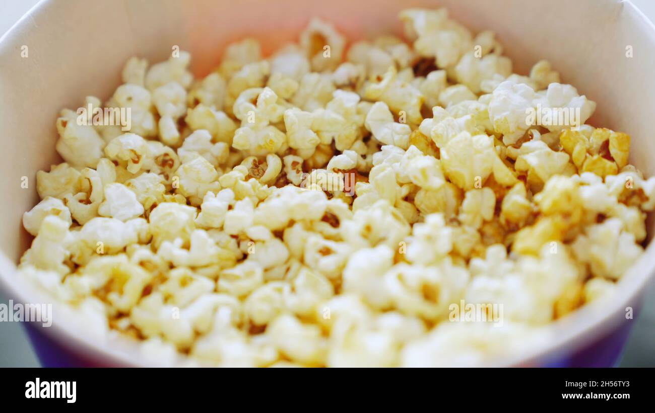 Close up of male hand taking popcorn from a bucket, concept of cinema ...