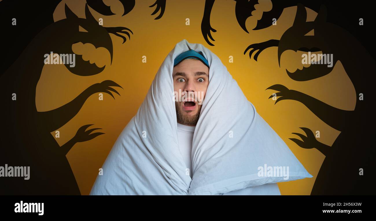Scared young man hiding from his inner fears, wrapped in blanket on ...