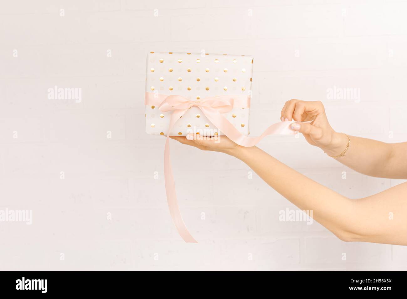 Female hands hold on white background.Gift box wrapped in paper. Gift ...