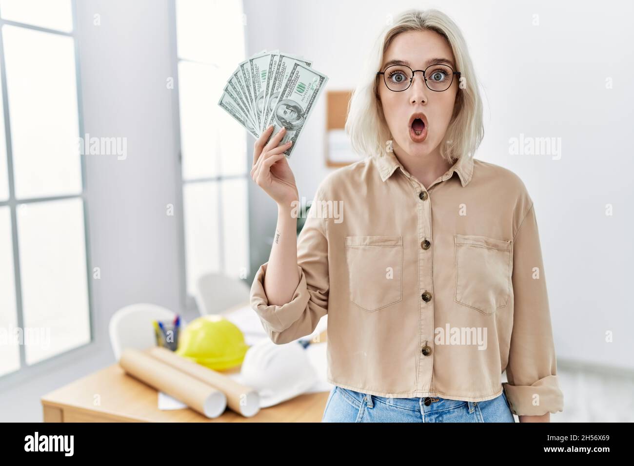 Young beautiful caucasian woman at construction office holding money ...