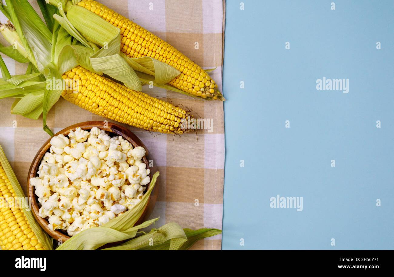 A bowl with delicious traditional popcorn and corn cobs on a blue ...