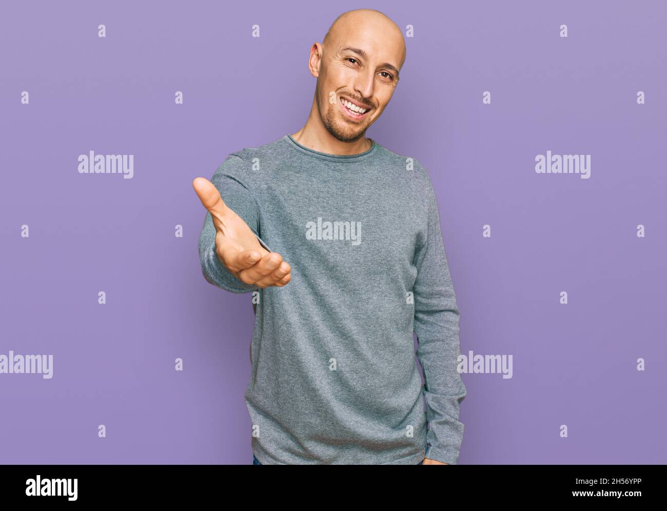 Bald man with beard wearing casual clothes smiling friendly offering ...