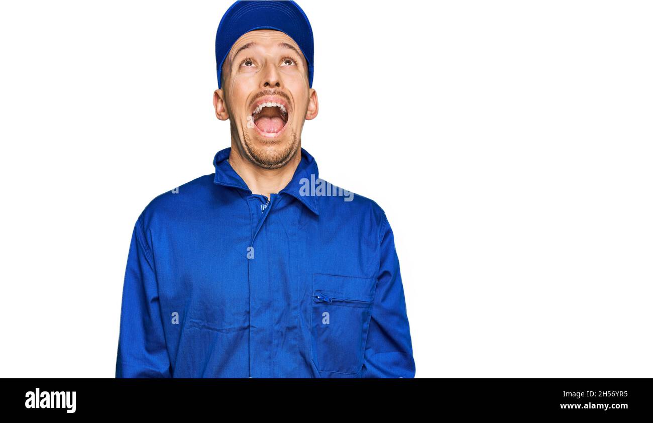 Bald man with beard wearing builder jumpsuit uniform angry and mad ...