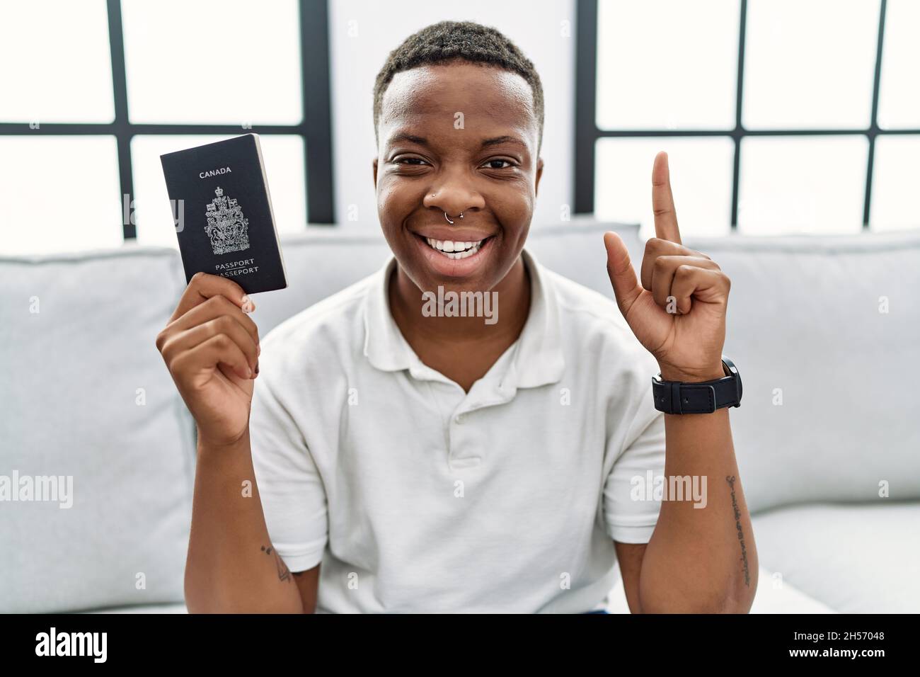 Young african man holding canada passport surprised with an idea or ...