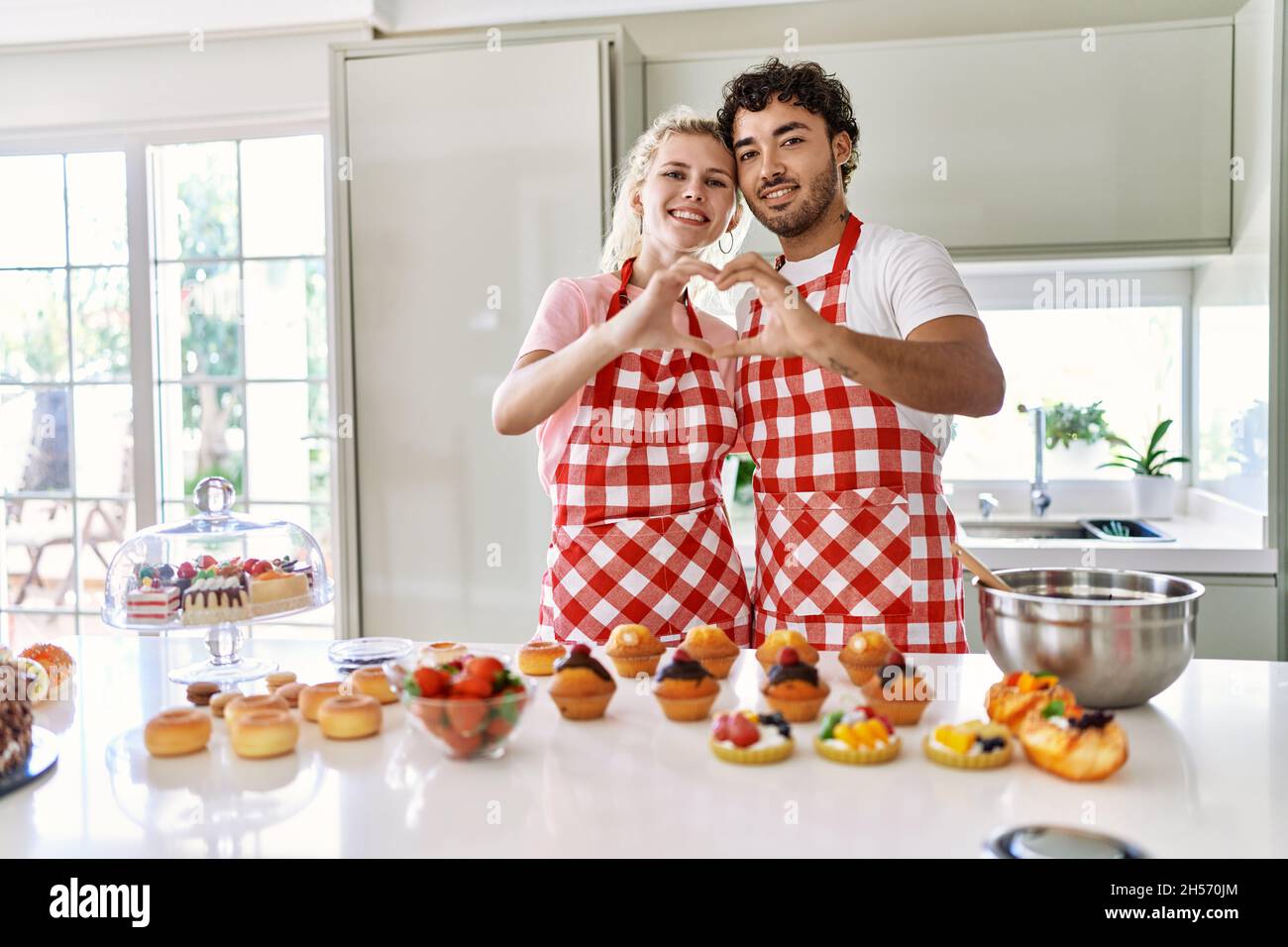 Couple of wife and husband cooking pastries at the kitchen smiling in ...