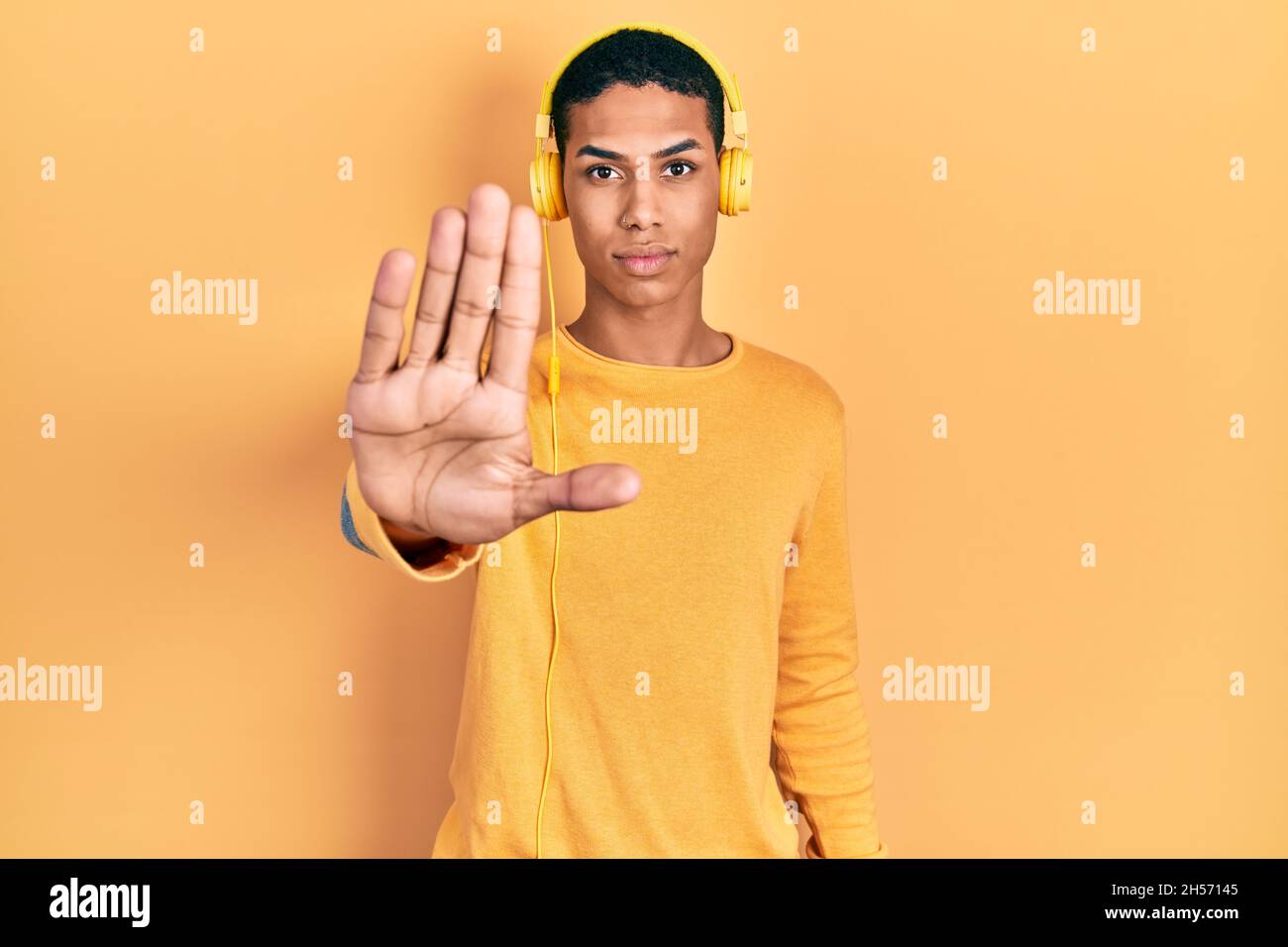 Young african american guy listening to music using headphones doing ...