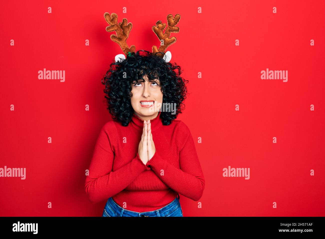 Young middle east woman wearing cute christmas reindeer horns begging ...