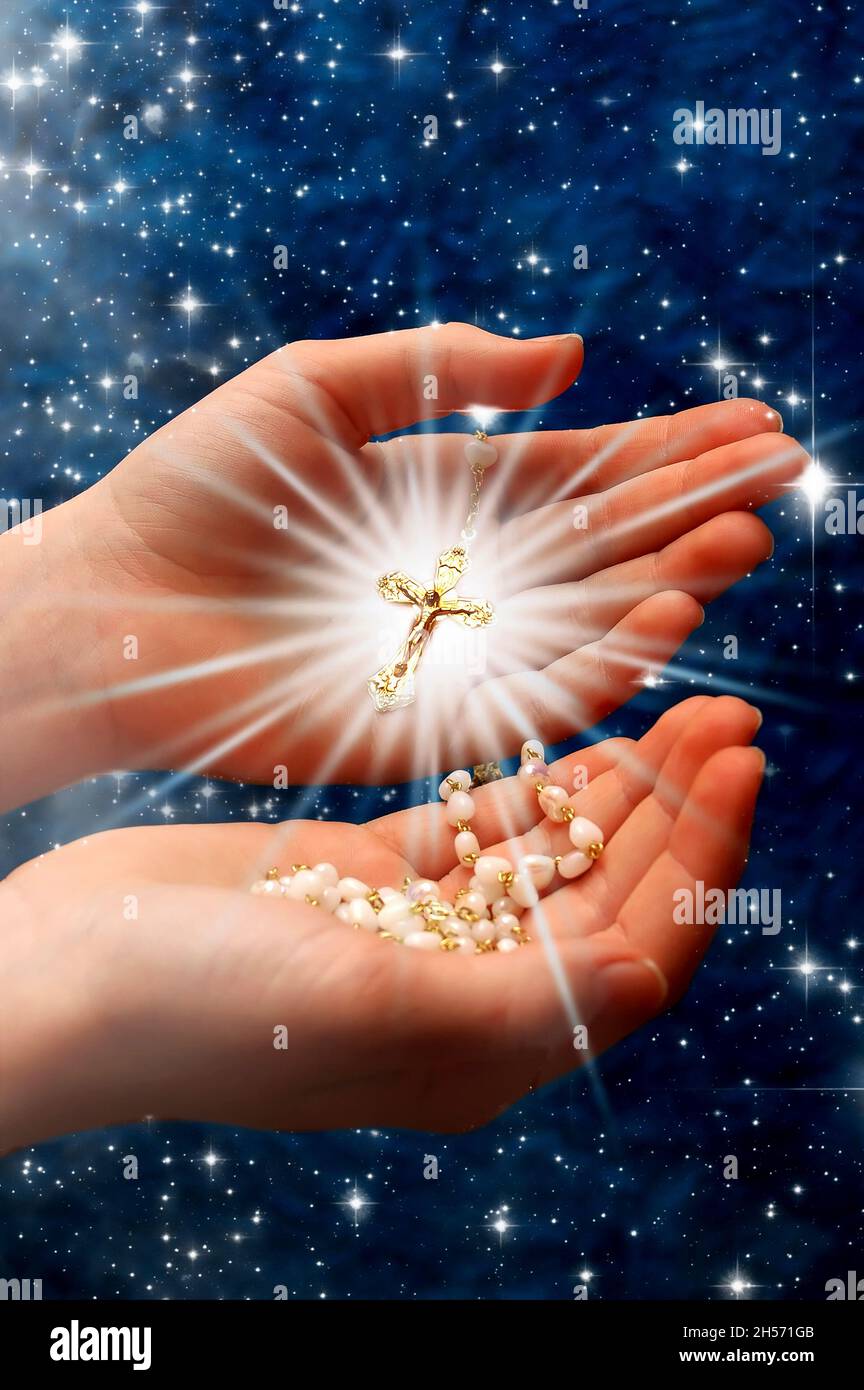 Hand keeping Christian cross rosemary over blue backround with rays of ...