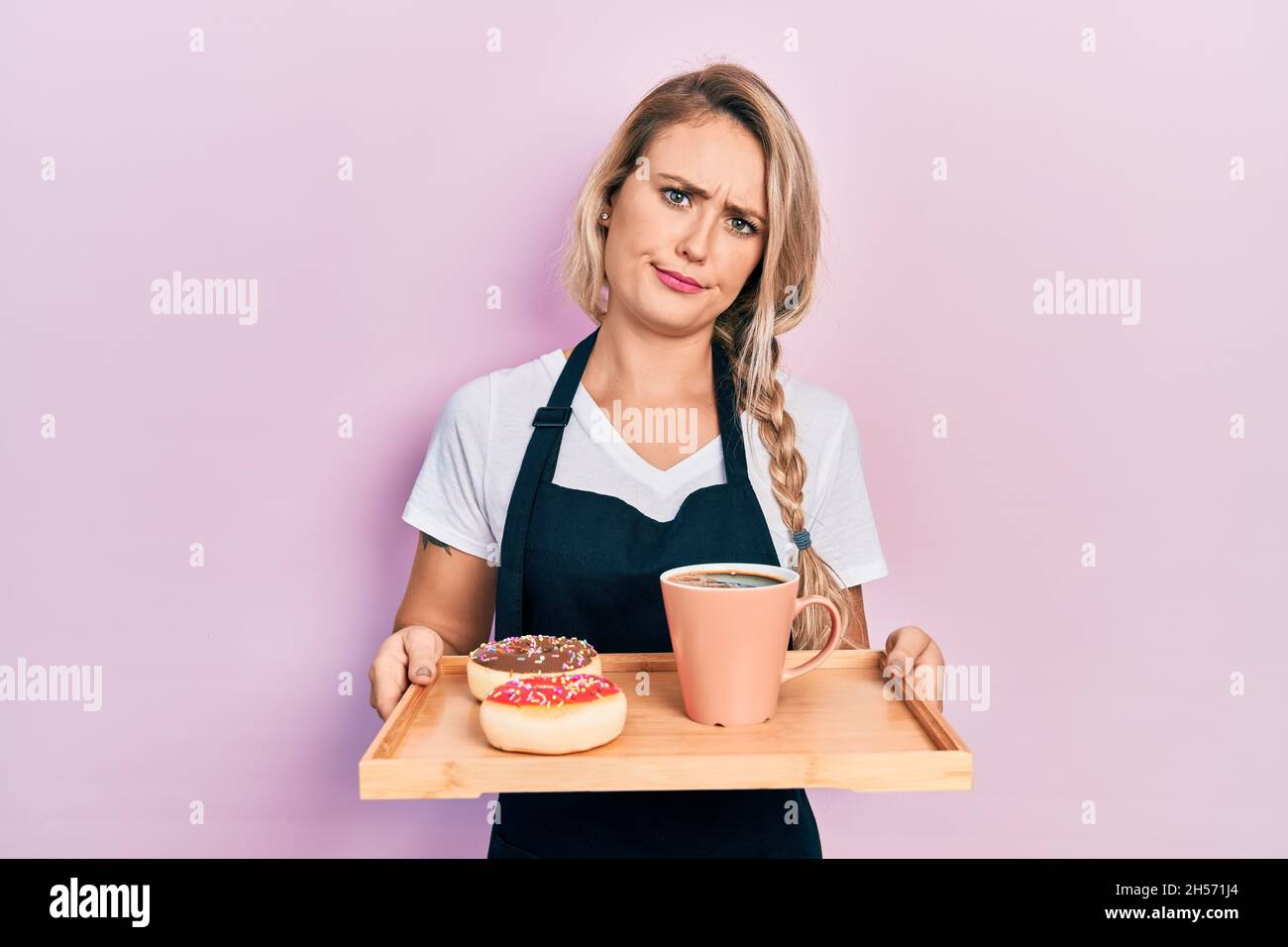 Beautiful young blonde woman wearing waitress apron holding breakfast ...