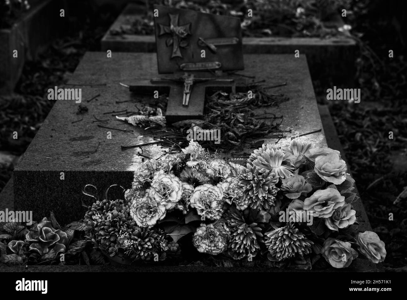 Autumn at cemetery. Faded leaves on grave and artificial flowers ...