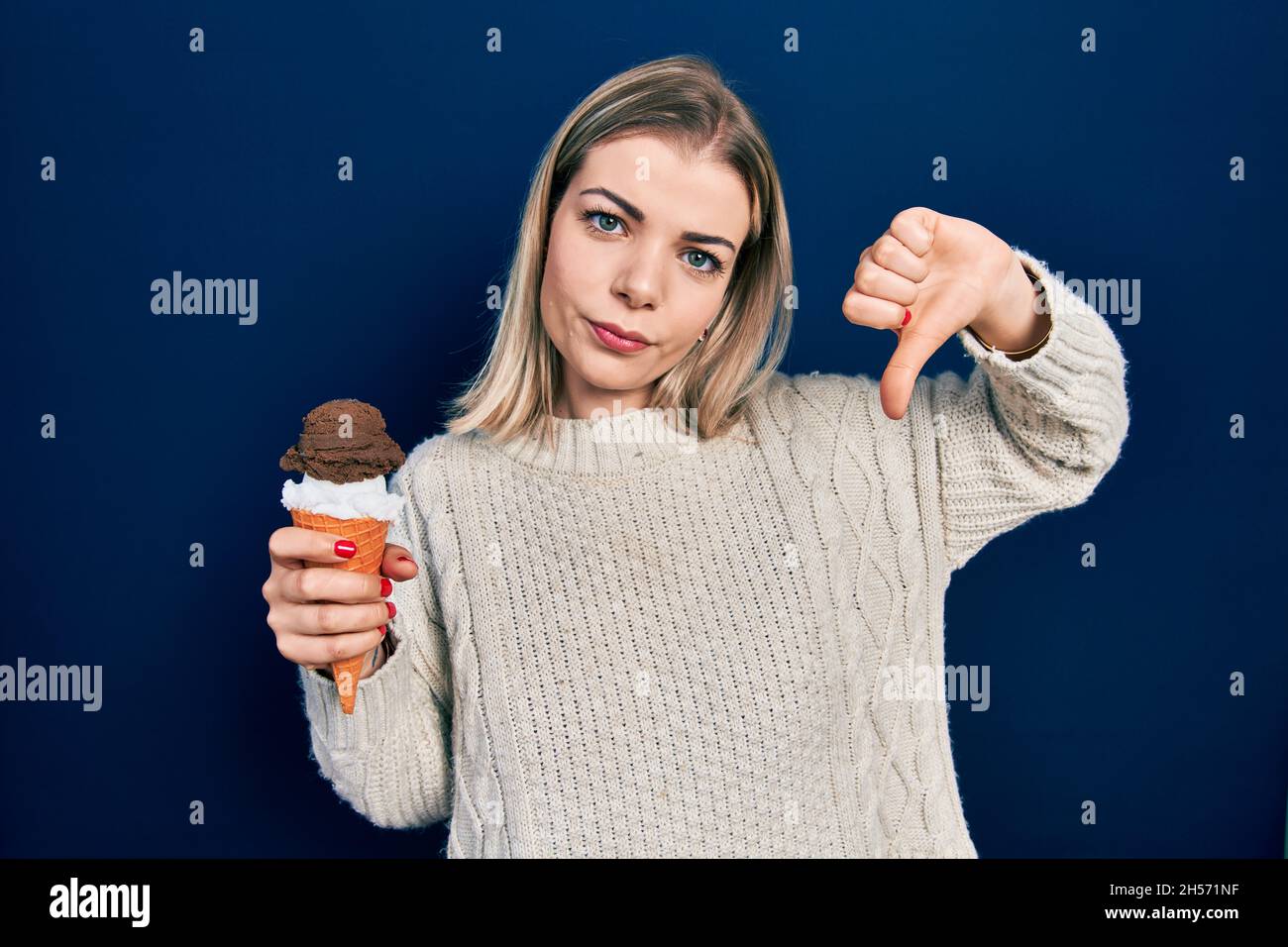 Beautiful caucasian woman eating ice cream with angry face, negative ...