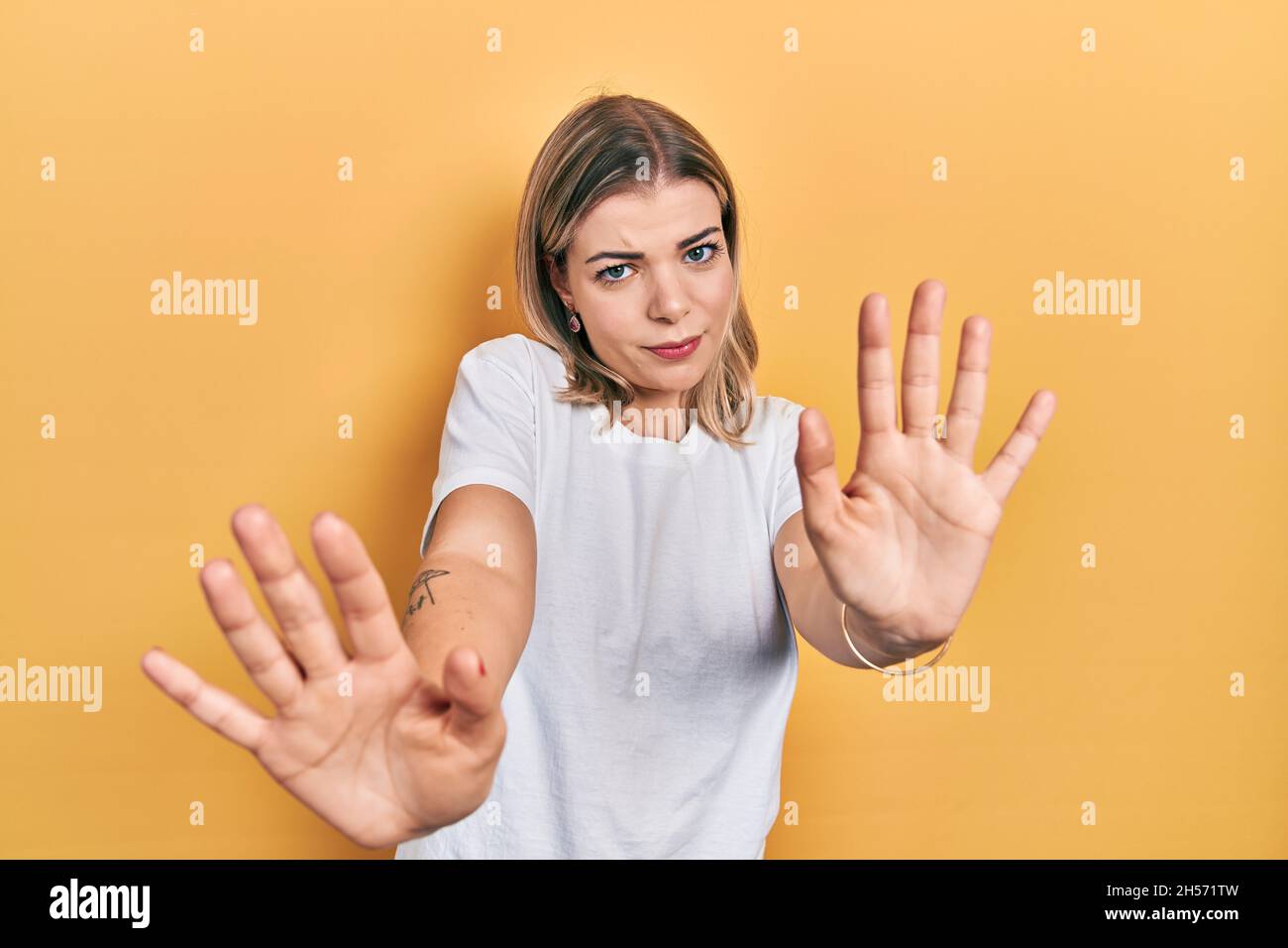 Beautiful caucasian woman wearing casual white t shirt afraid and ...