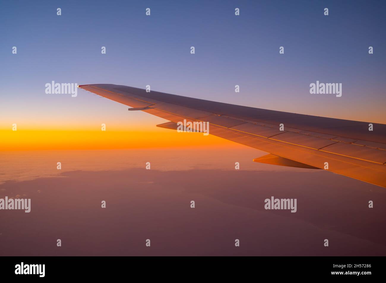View of the wing of an airplane during flight from the window at sunset ...