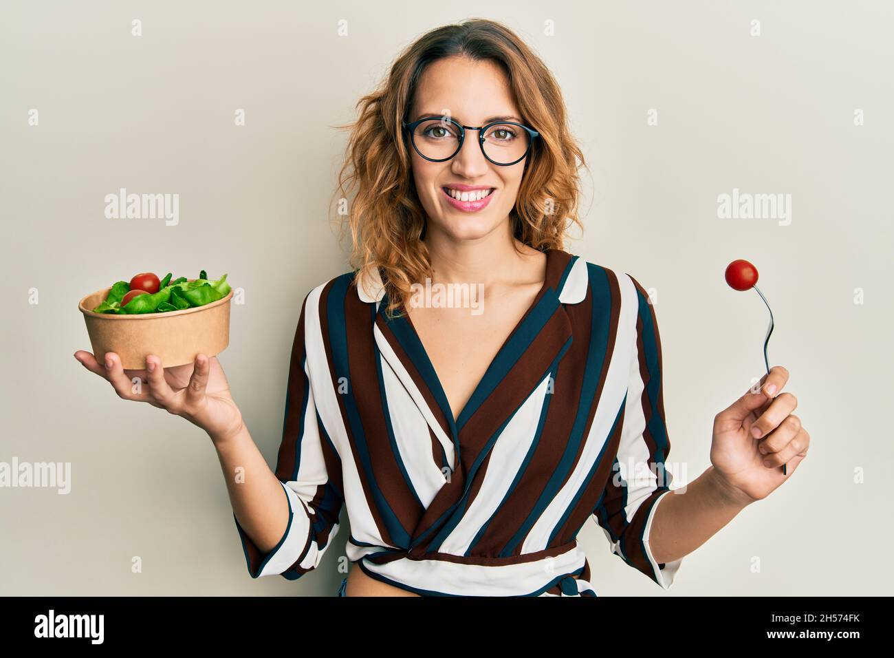 Young caucasian woman wearing business clothes eating salad smiling ...