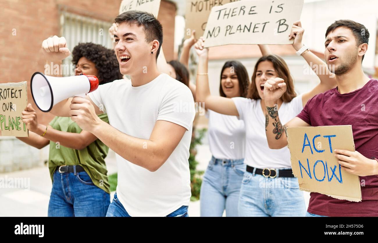 Group of young activists people protesting holding banner and using ...