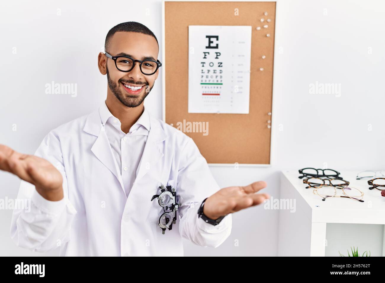 African american optician man standing by eyesight test smiling ...
