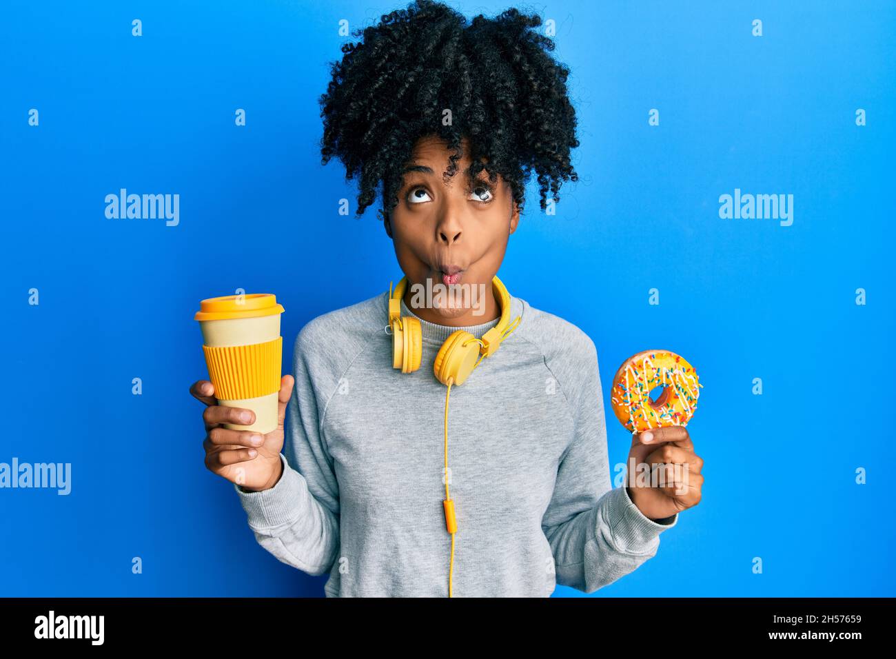 African american woman with afro hair eating doughnut and drinking ...
