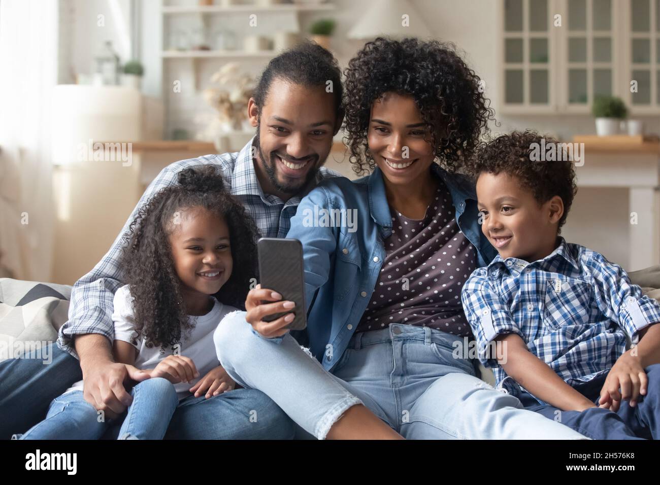 Happy parents and cute sibling kids watching online media content Stock ...