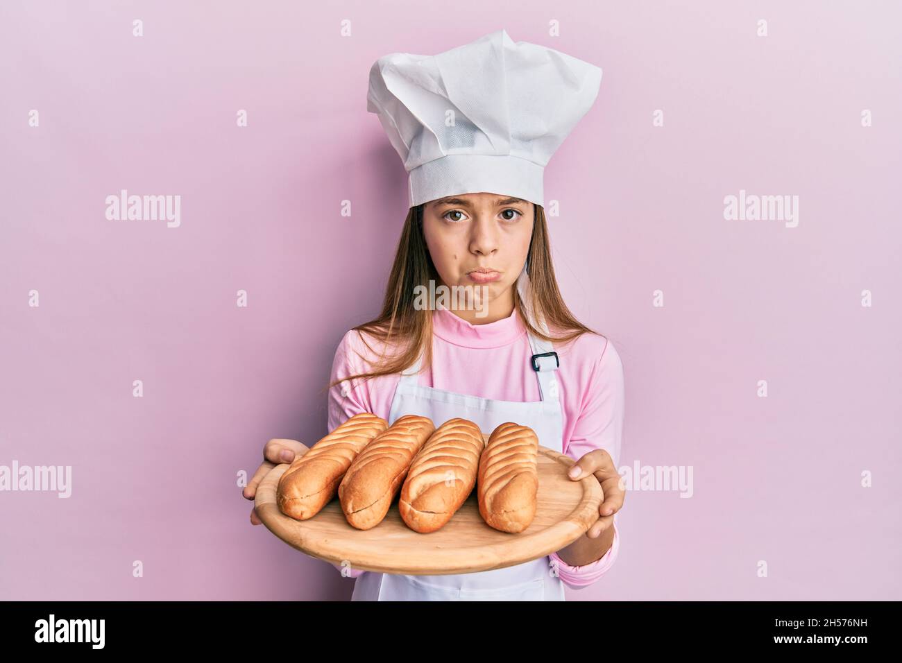 Beautiful brunette little girl wearing baker uniform holding homemade ...