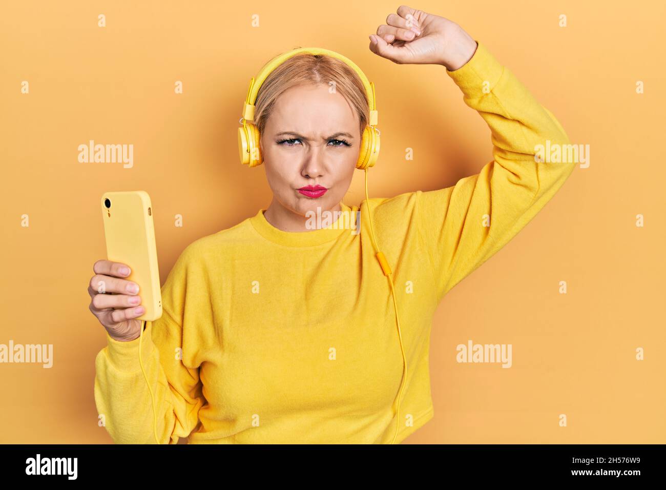 Young blonde woman dancing wearing headphones skeptic and nervous ...