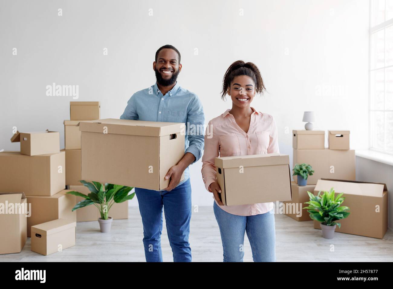 Satisfied happy young african american husband and wife carry boxes ...