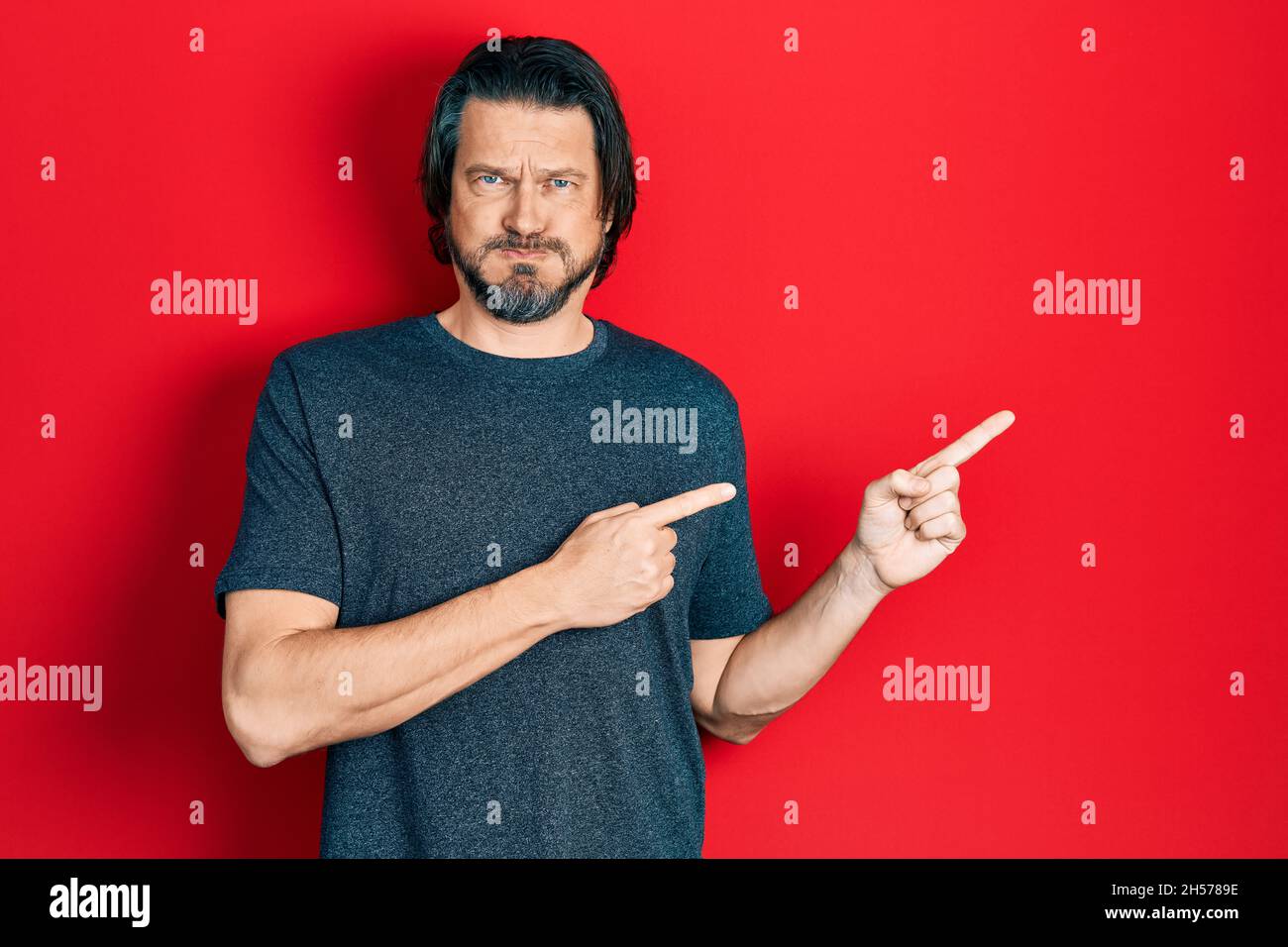 Middle age caucasian man pointing with fingers to the side puffing ...