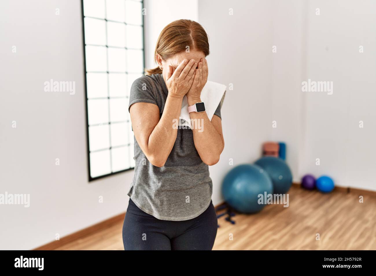 Middle age woman wearing sporty look training at the gym room with sad ...