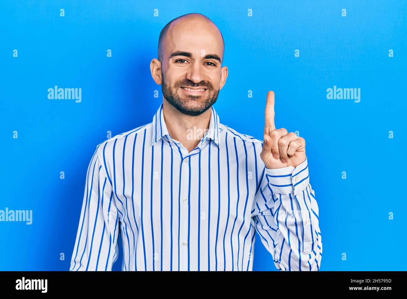 Young bald man wearing elegant clothes smiling with an idea or question ...