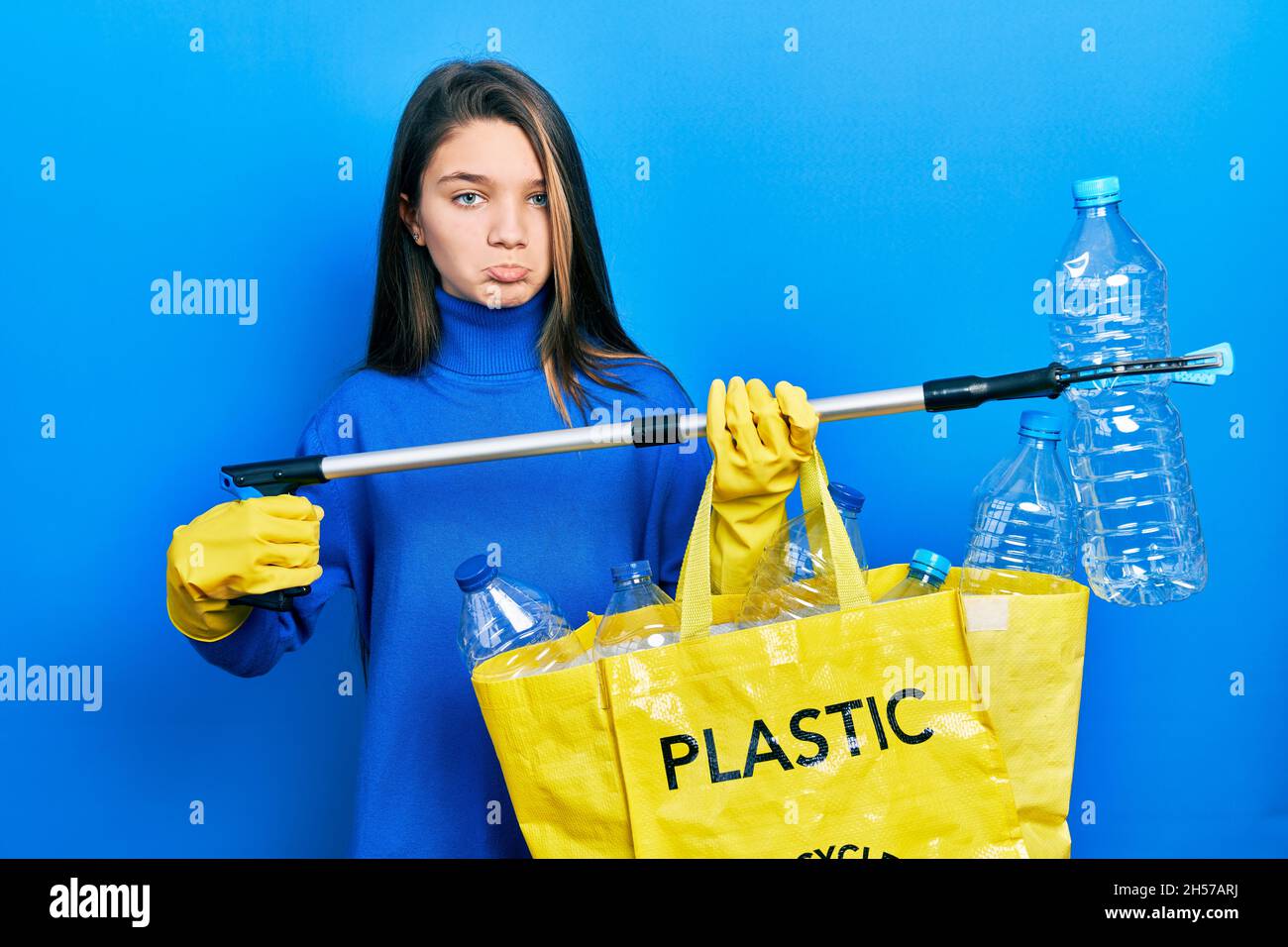 Young brunette girl holding recycling bag with plastic bottles and ...