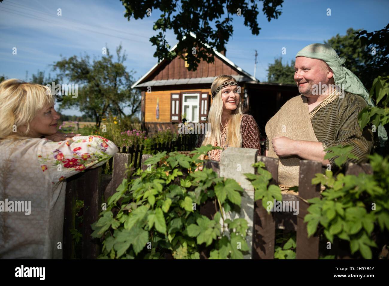Neighbors chat with smiles on their faces while standing by an old ...