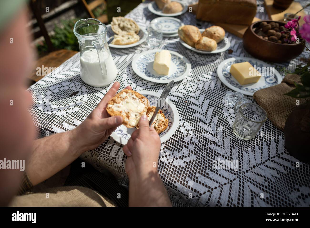 A man while spreading butter on a roll. A country breakfast Stock Photo ...