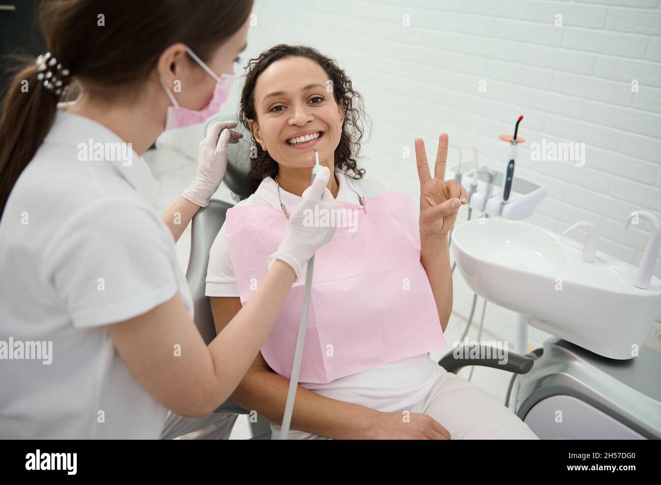 Happy delighted African woman patient shows peace sign sitting in ...