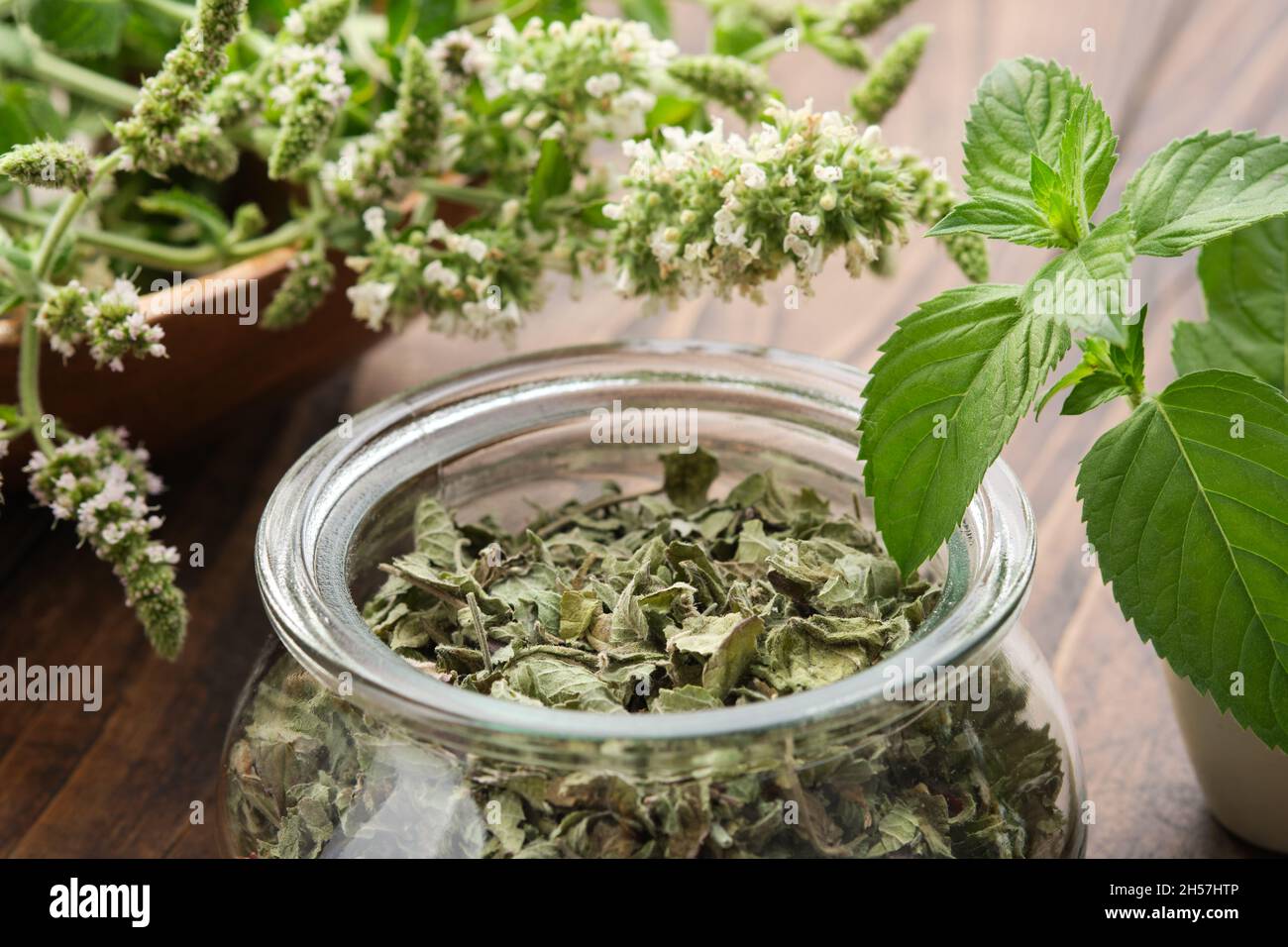 Glass jar of dried mint leaves. Wooden bowl of blossom peppermint ...