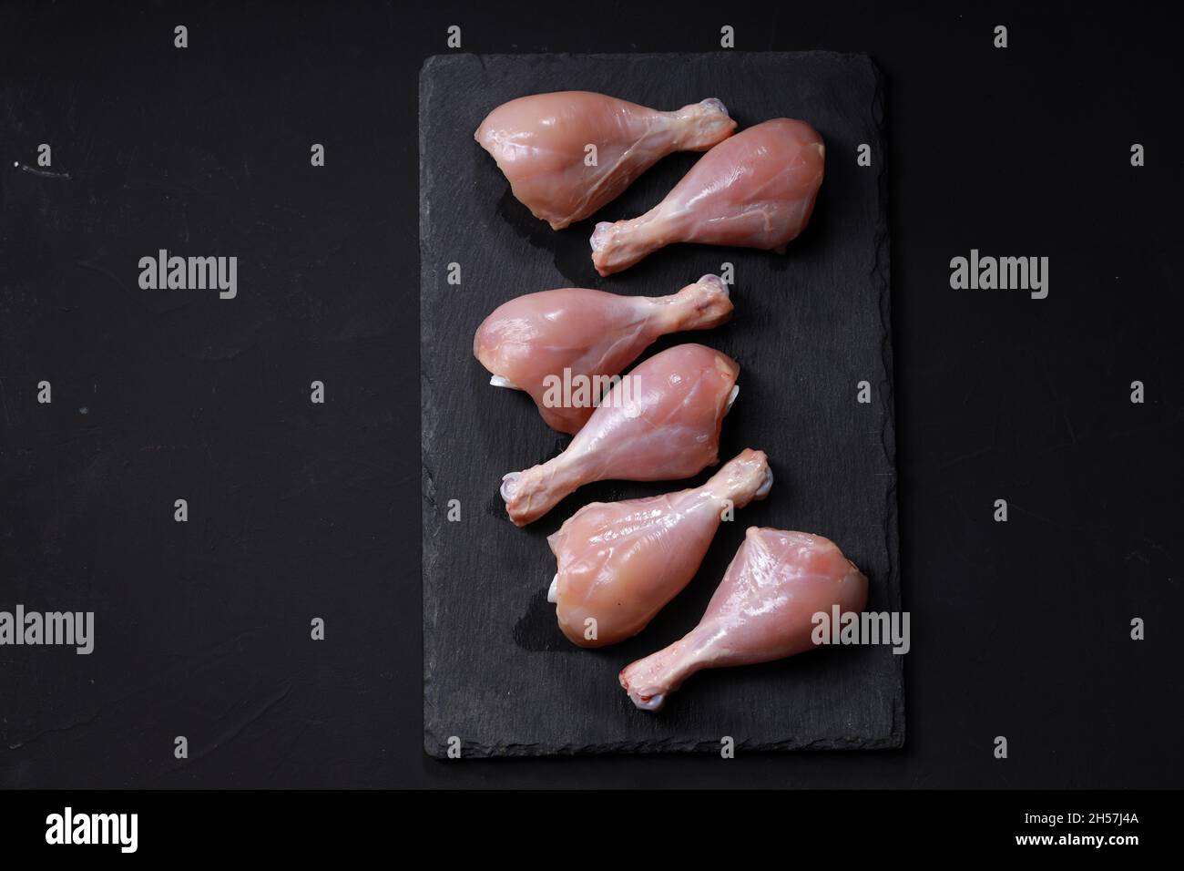 Raw chicken drum stick or leg pieces arranged on graphite sheet ...